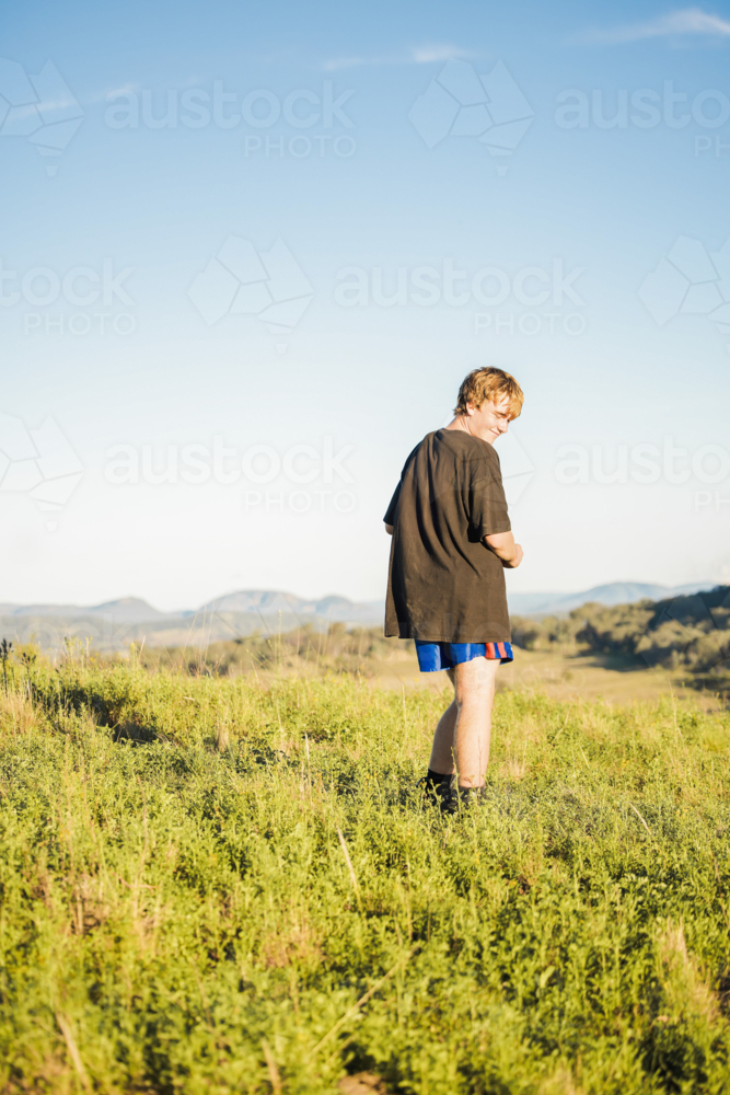 Image of Teenage boy standing on high remote ridge line with hills in ...