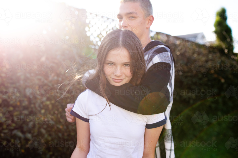 Image of Teenage brother hugging sister from behind in the garden ...
