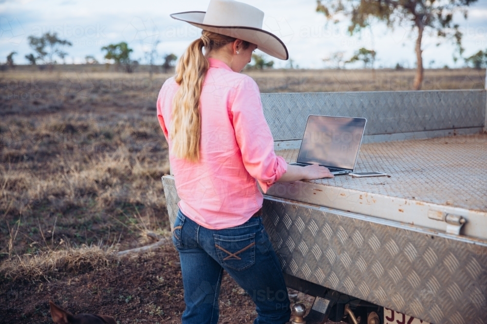Image of Teenage Female farmer using laptop in the paddock - Austockphoto