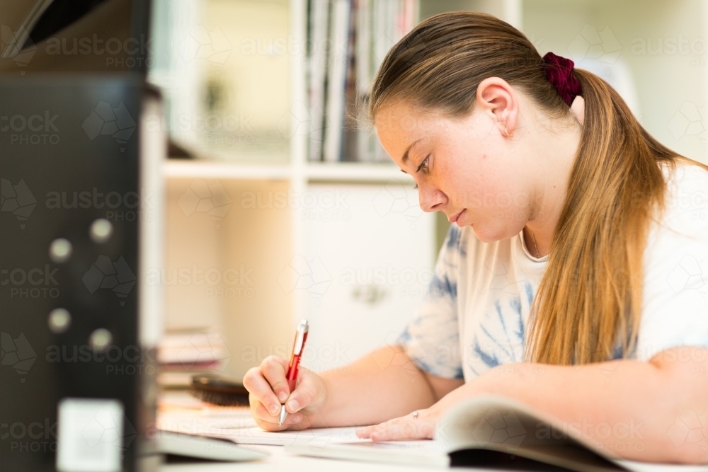 Image of Teenage girl at desk writing notes - Austockphoto