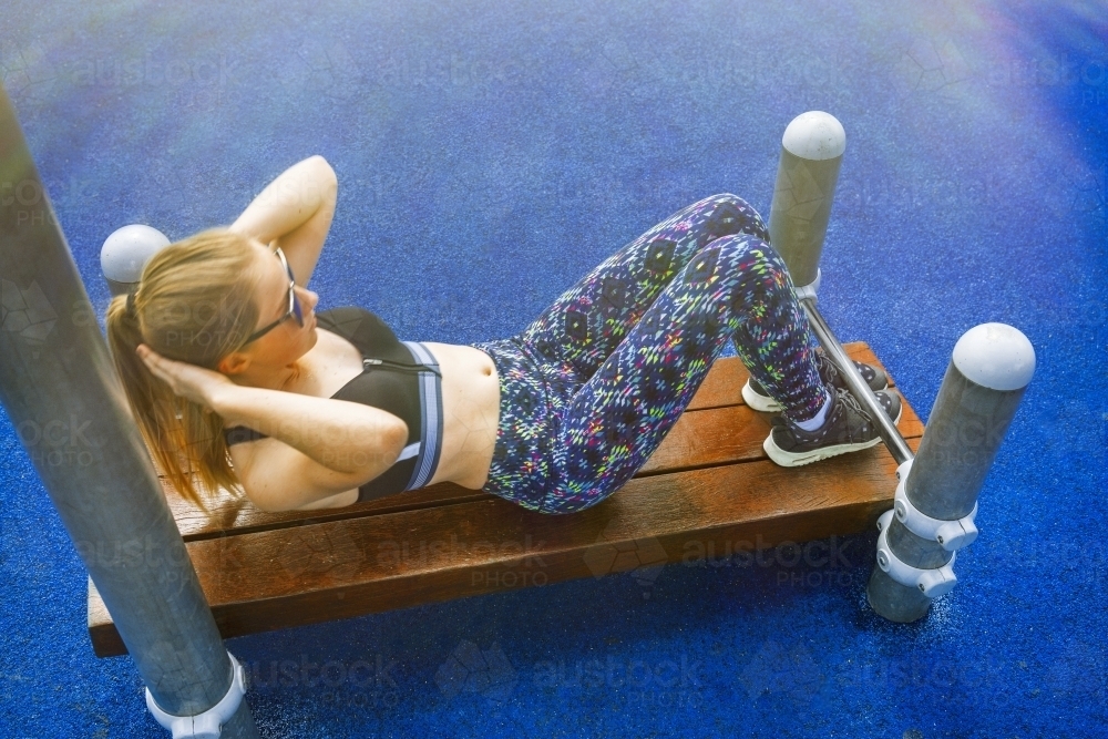 Image of Teenage girl doing sit ups outdoors - Austockphoto