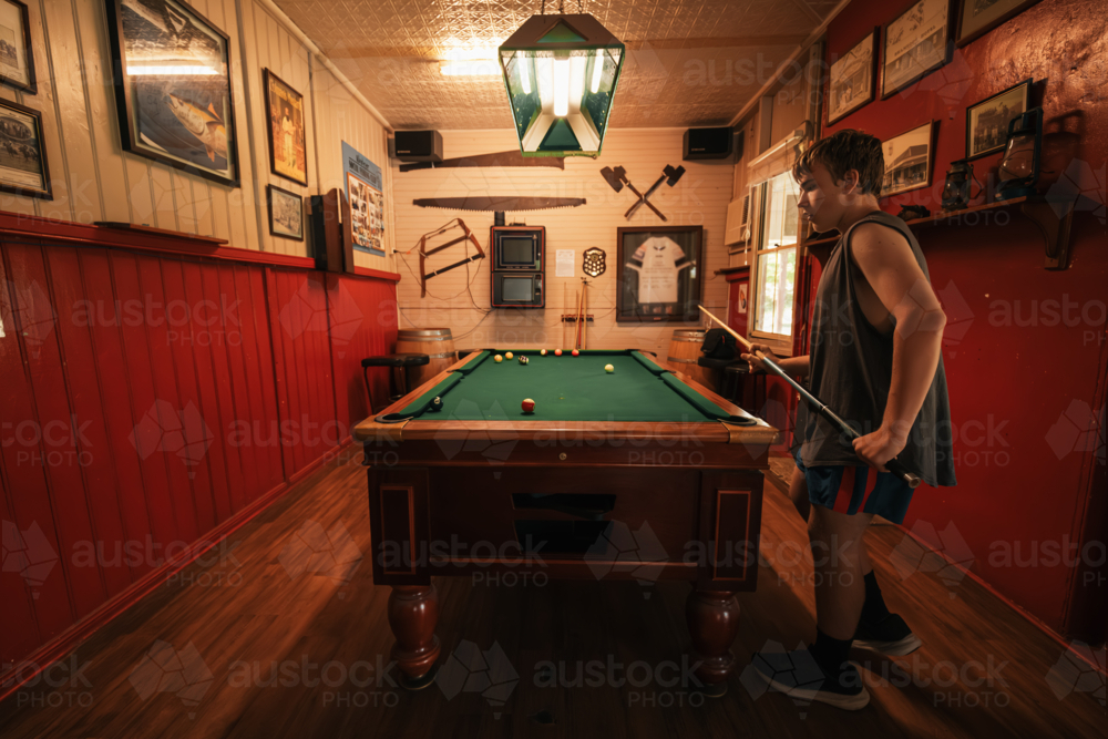 Image of Teenage male playing 8 ball pool on billiard table in ...