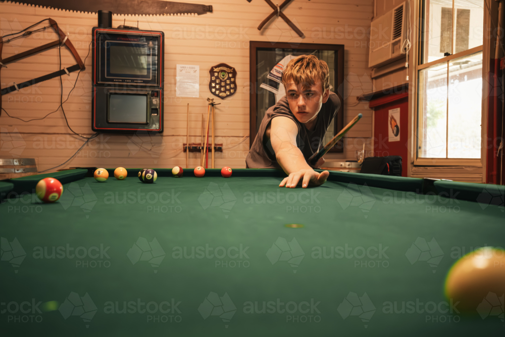 Image of Teenage male playing 8 ball pool on billiard table in ...