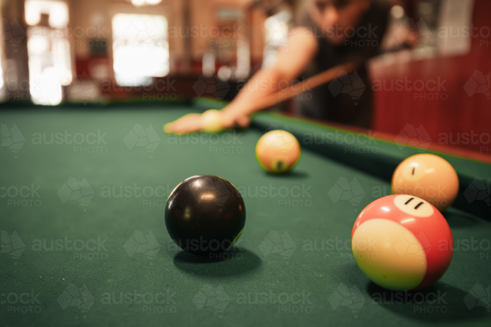 Image of Teenage male playing 8 ball pool on billiard table in ...
