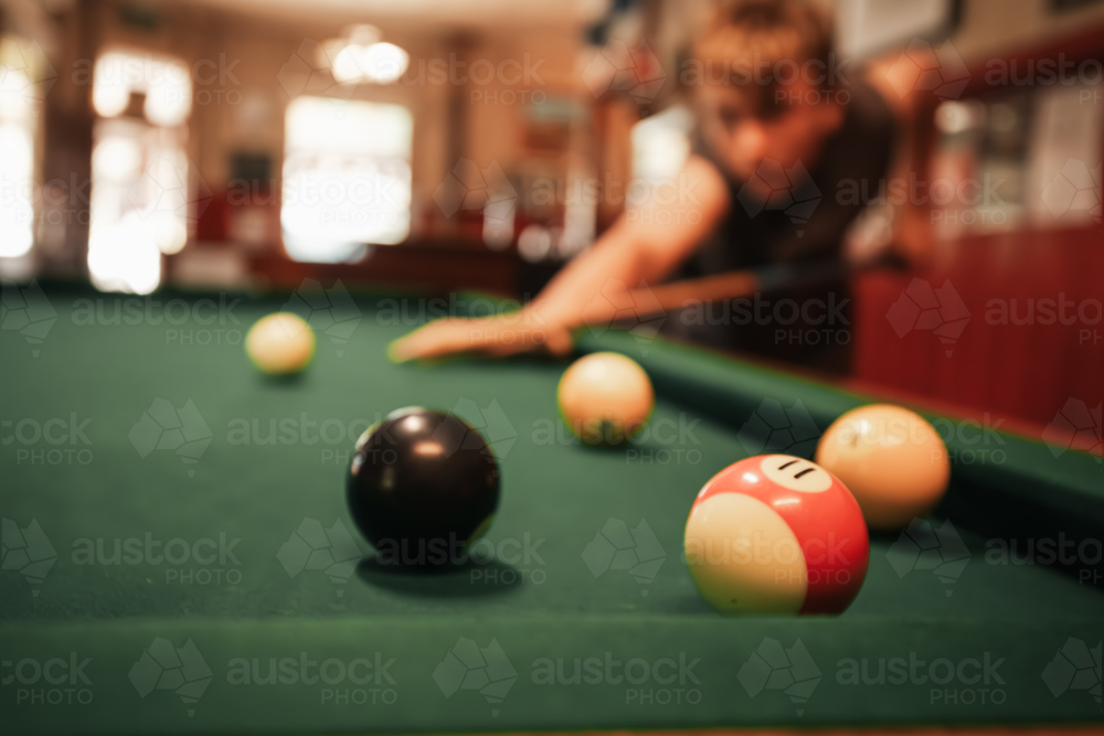Image of Teenage male playing 8 ball pool on billiard table in ...