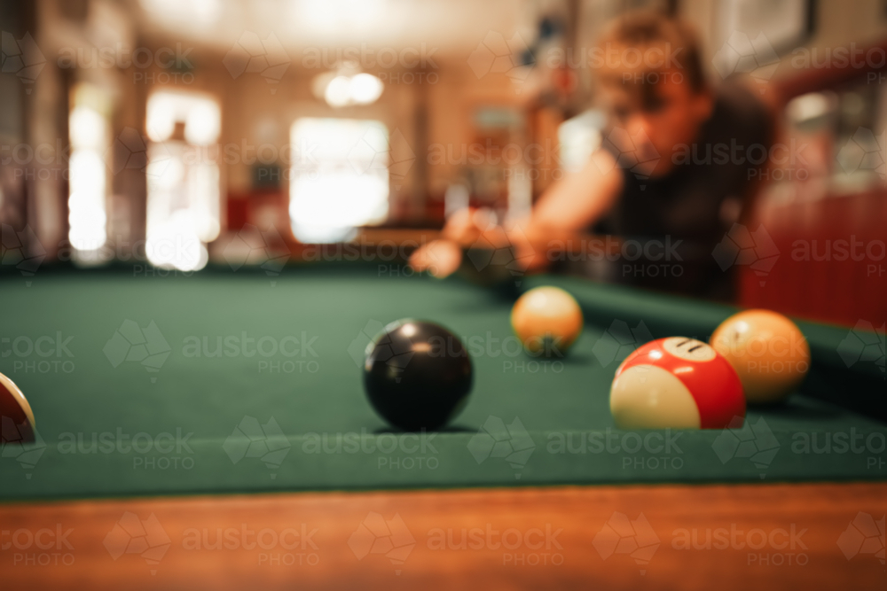 Image of Teenage male playing 8 ball pool on billiard table in ...