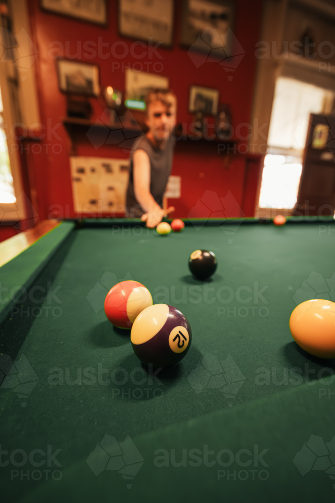 Image of Teenage male playing 8 ball pool on billiard table in ...