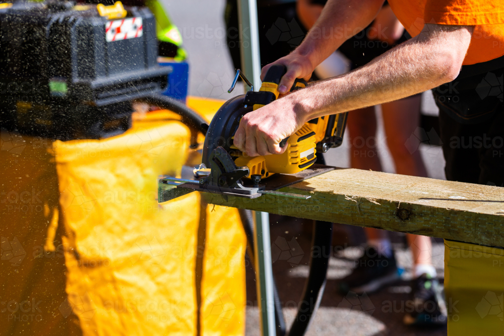 Image of Teenaged trade apprentice using circular saw tool to cut wood ...