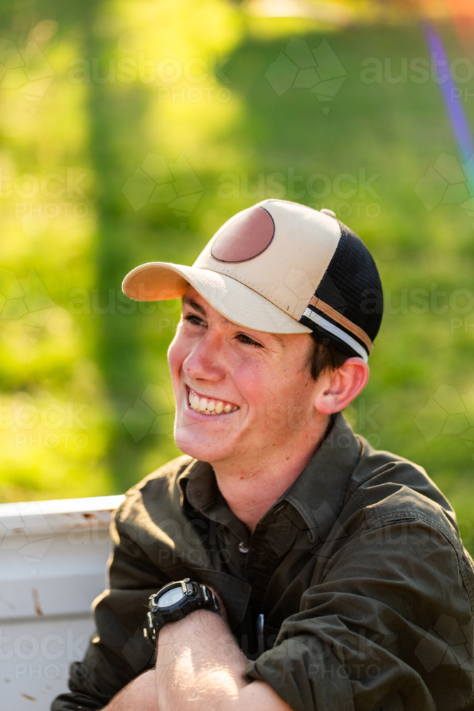 Image of Teenaged young man leaning on ute tray in afternoon in green ...