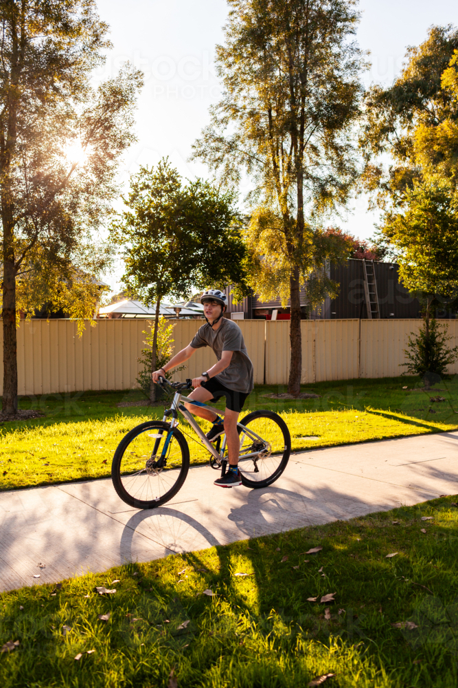 Image of Teenager riding his bicycle along bike path late in the day ...
