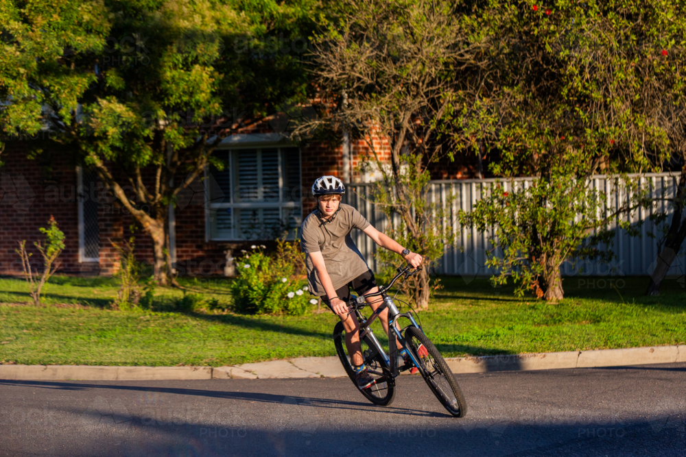 Image of Teenager riding pushbike on suburban street in country town of ...