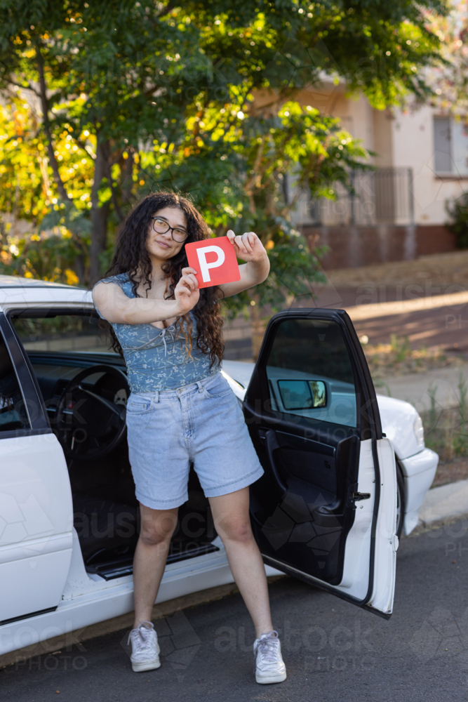 Image of teenager standing near car proudly displaying new P Plate ...