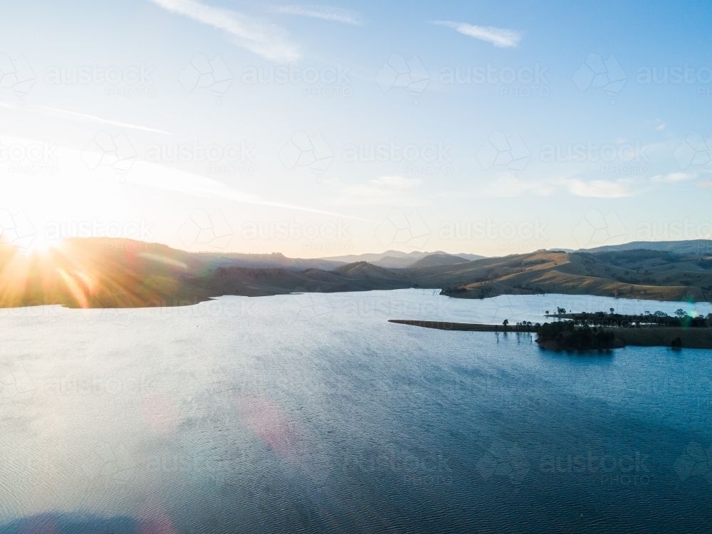 Image of The light of day fading as the sun sets behind hills and blue ...