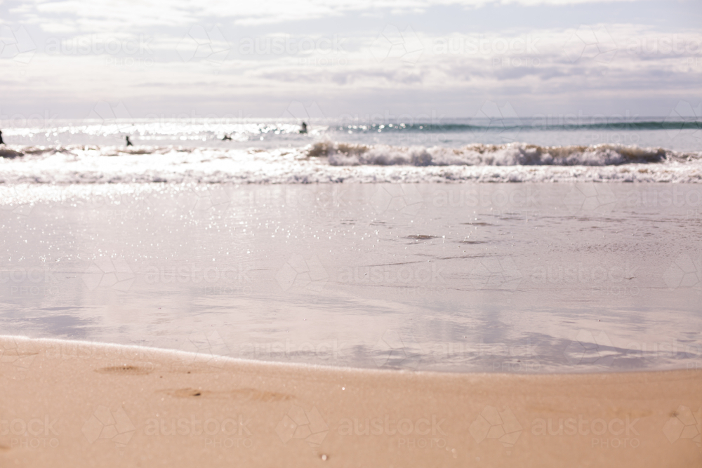 Image of the sky reflected on the water at the beach with surfers and ...