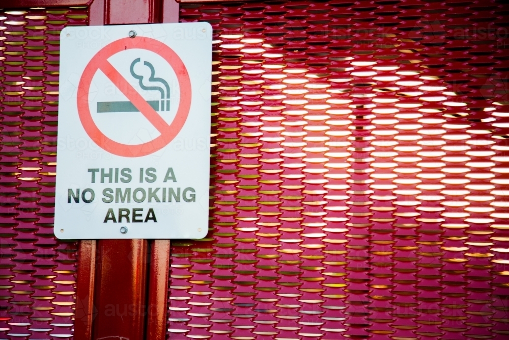 Image of This is a no smoking area sign on red bus stop shelter ...