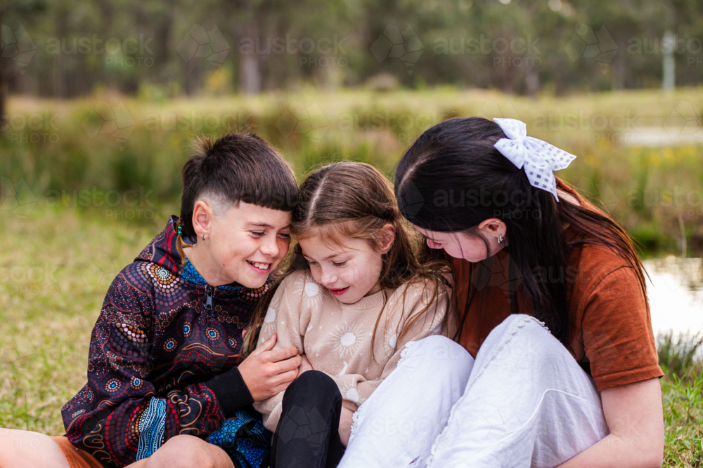 Image of Three aboriginal kids hugging and smiling together outside ...