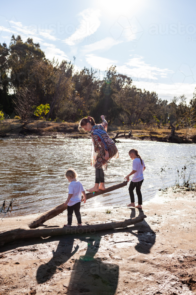 Image of Three aboriginal kids playing down by river on tree log ...