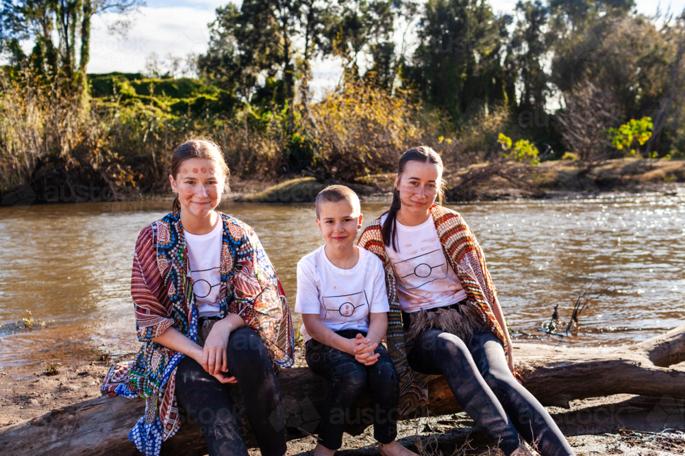 Image of Three aboriginal siblings sitting on log together by Hunter ...