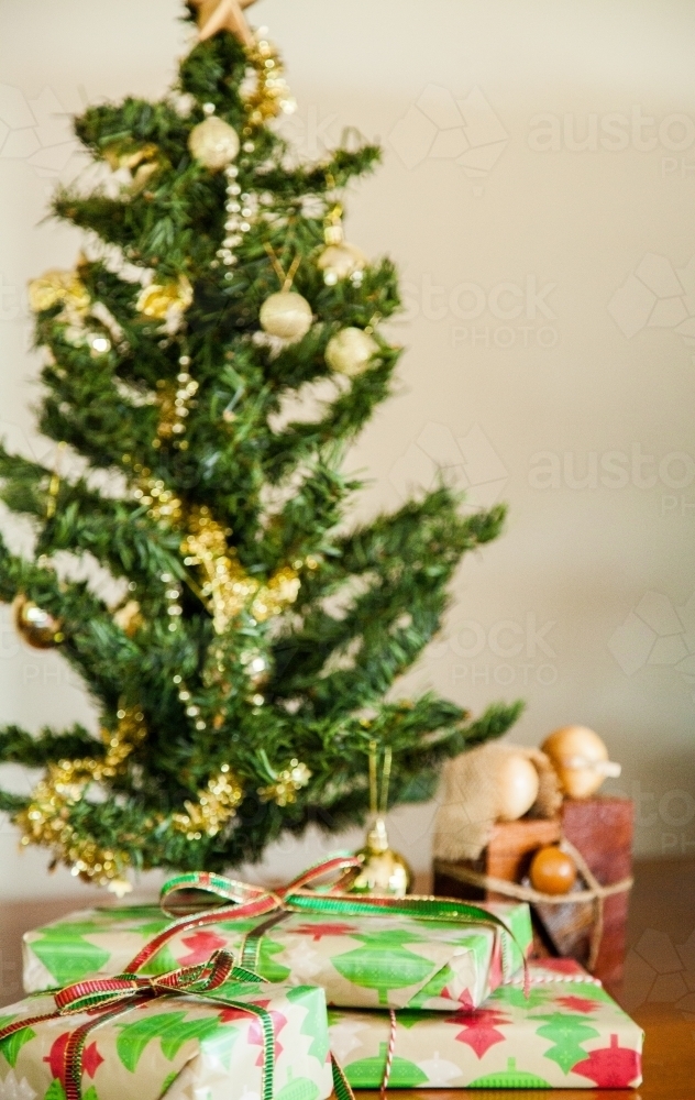 Image of Three brightly wrapped Christmas gifts under a small decorated ...