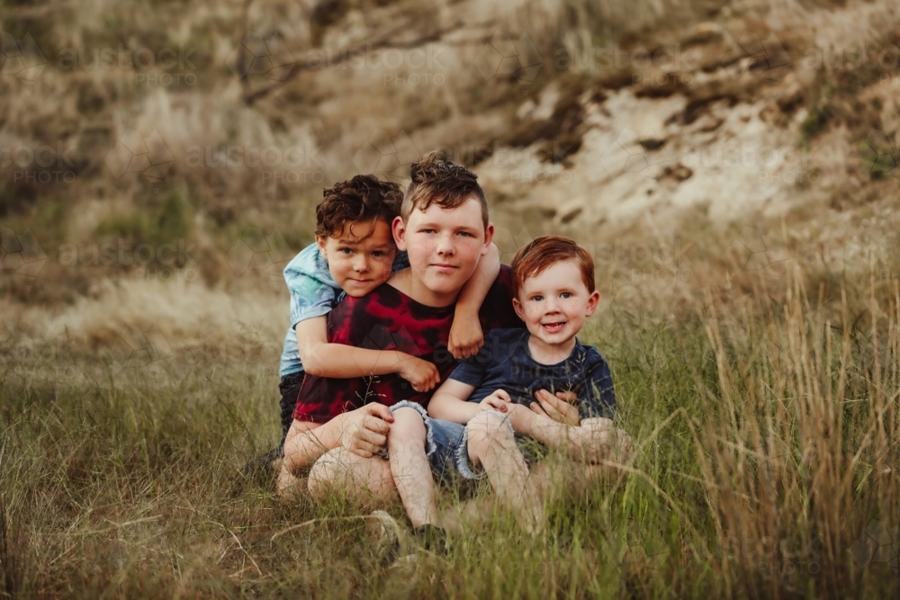 Image of Three brothers sitting together on a rock in the Australian ...