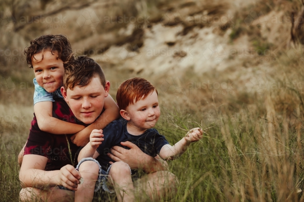 Image of Three brothers sitting together on a rock in the Australian ...