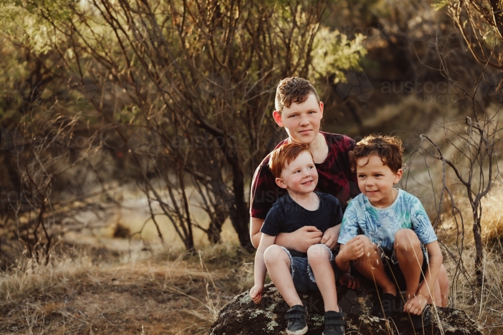 Image of Three brothers sitting together on a rock in the Australian ...