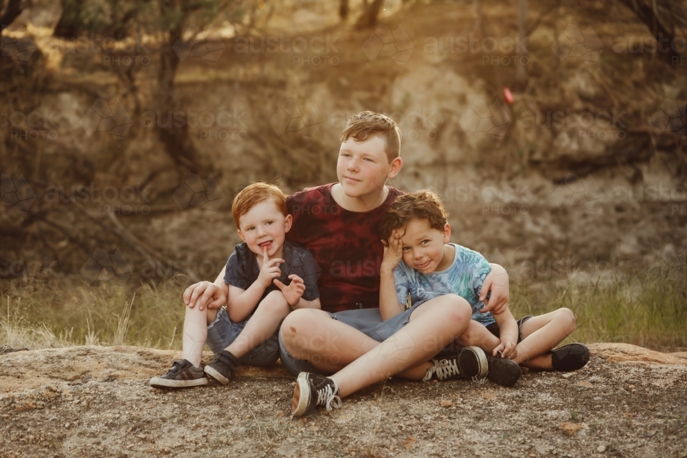 Image of Three brothers sitting together on a rock in the Australian ...
