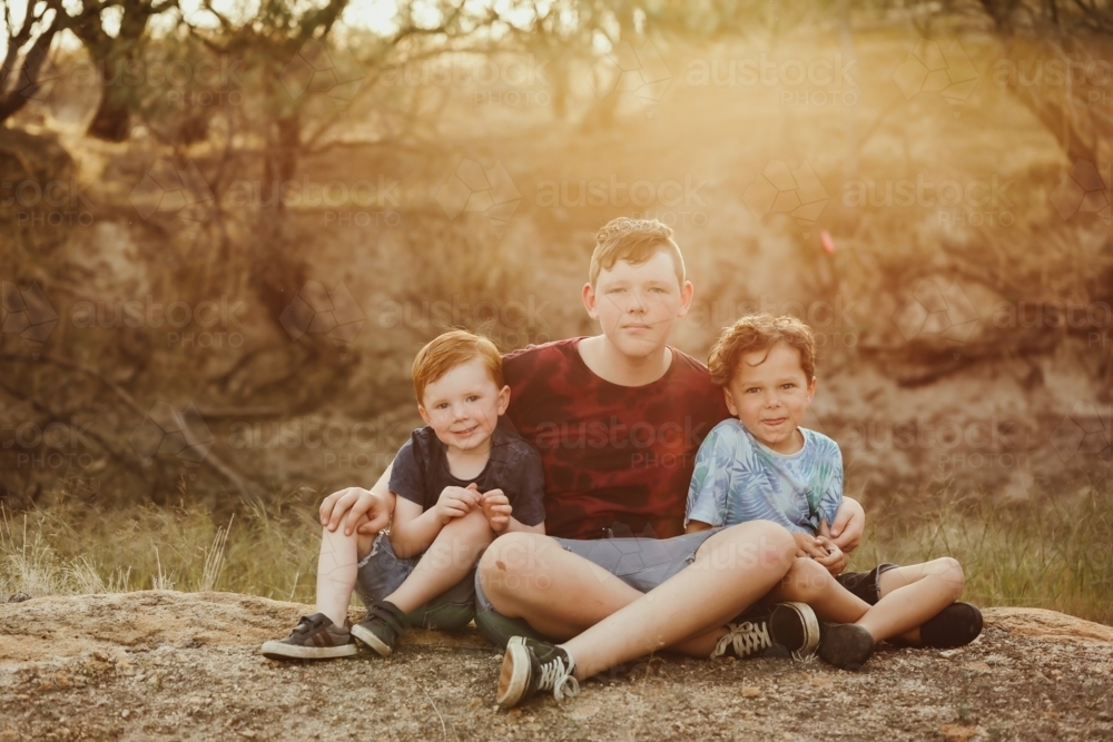 Image of Three brothers sitting together on a rock in the Australian ...