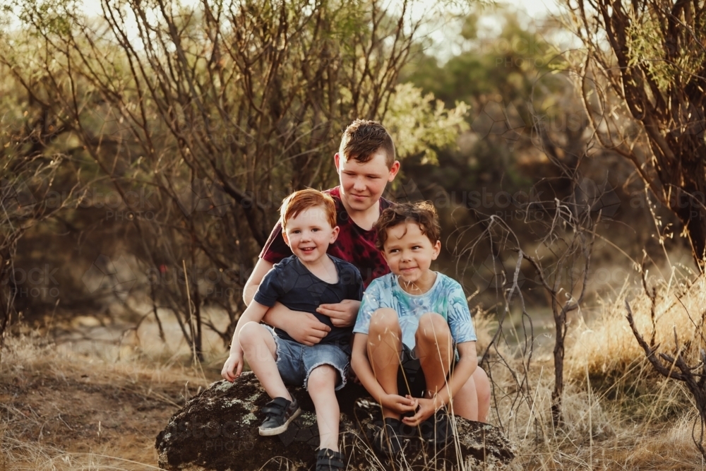 Image of Three brothers sitting together on a rock in the Australian ...