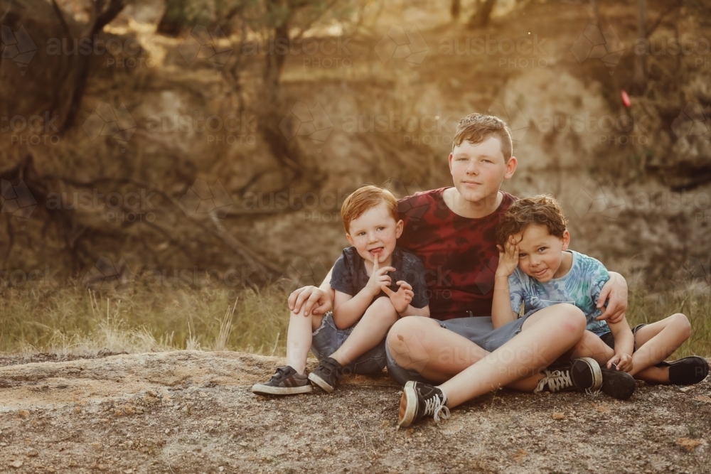 Image of Three brothers sitting together on rock in the Australian bush ...