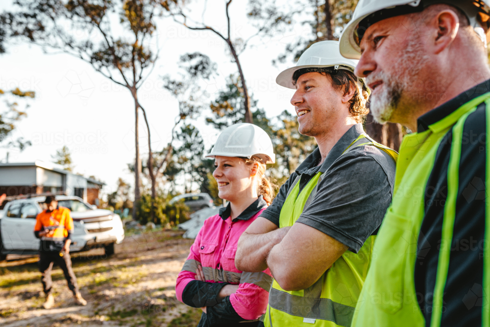 Image of Three construction workers standing on worksite with arms ...