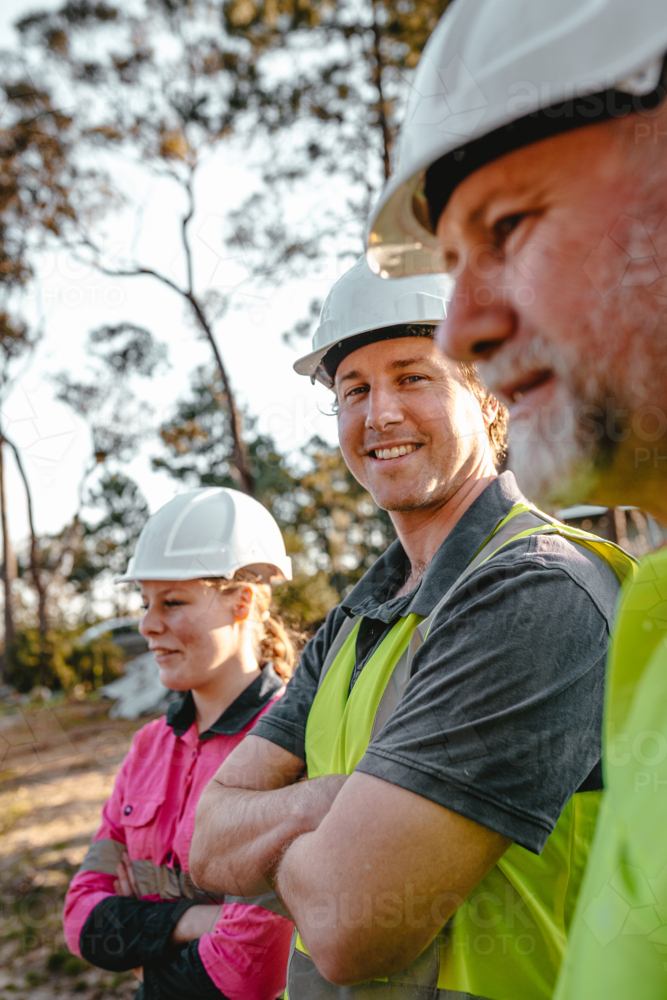 Image of Three construction workers standing on worksite with arms ...