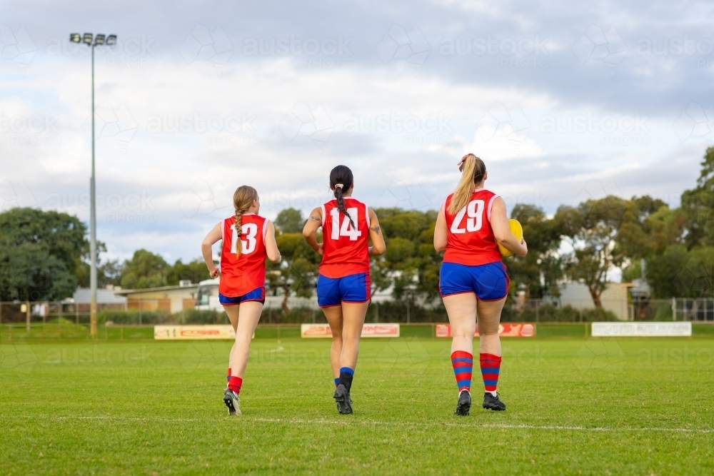 Image of three female footballers running onto playing field - Austockphoto