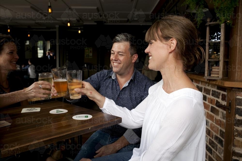 Image of Three friends toasting a drink at local craft beer pub ...