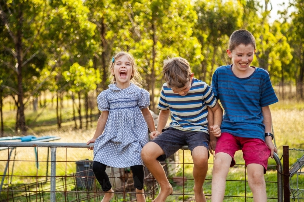 Image of Three happy children laughing together outside - Austockphoto