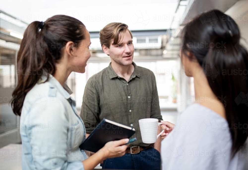 Image of Three happy office workers talking together in an industrial ...