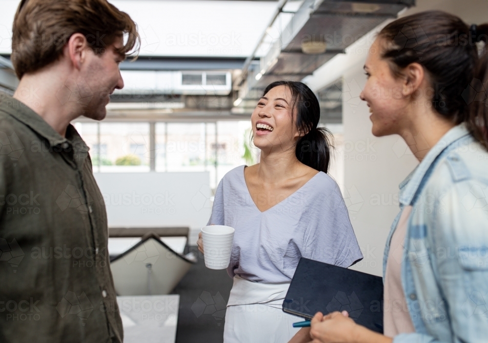 Image of Three happy office workers talking together in an industrial ...