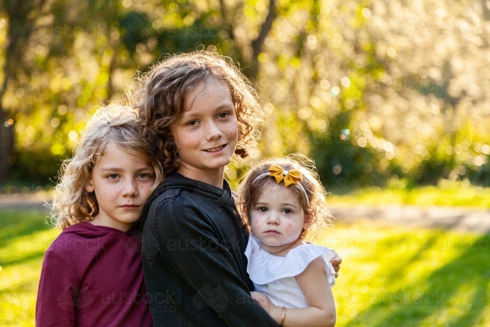 Image of Three happy siblings with curly hair smiling together two boys ...
