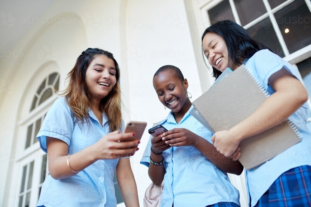 Image of Three High School friends laughing whilst checking their ...
