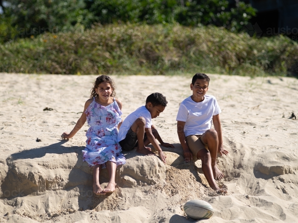 Image of Three indigenous children playing in the sand - Austockphoto