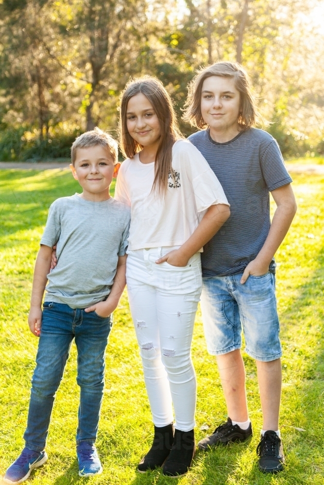 Image of Three kids standing together in park - Austockphoto