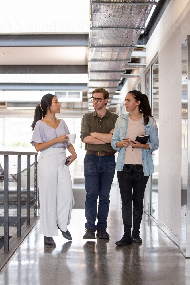 Image of Three office workers in an industrial co-working space walking ...