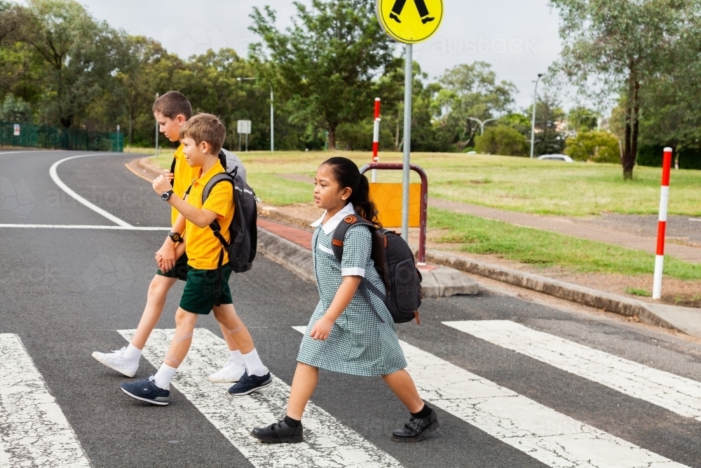 Image of Three public school kids walking to school - crossing the road ...