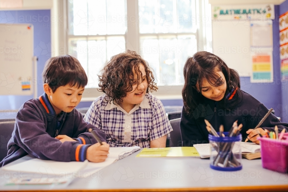 Image of Three school students sitting at their desk in the classroom ...