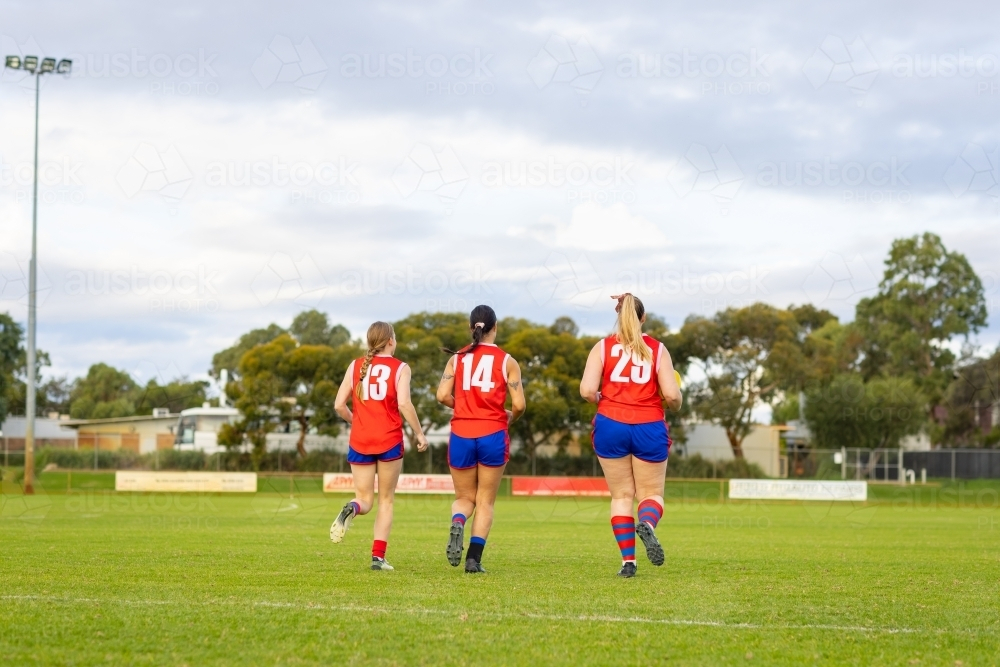 Image of three women footballers jogging on the field - Austockphoto