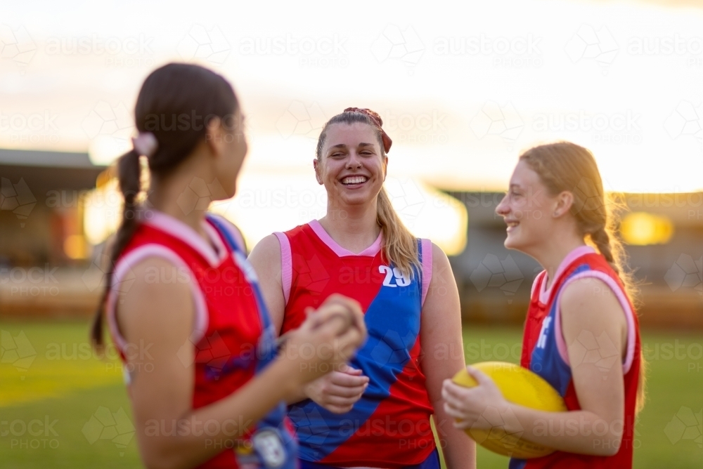 Image of three young female teammates in evening light in football ...