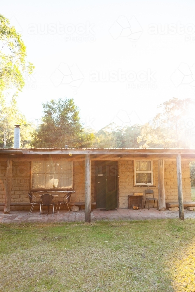 Image of Tiny cabin in bushland with sun flare over verandah - Austockphoto