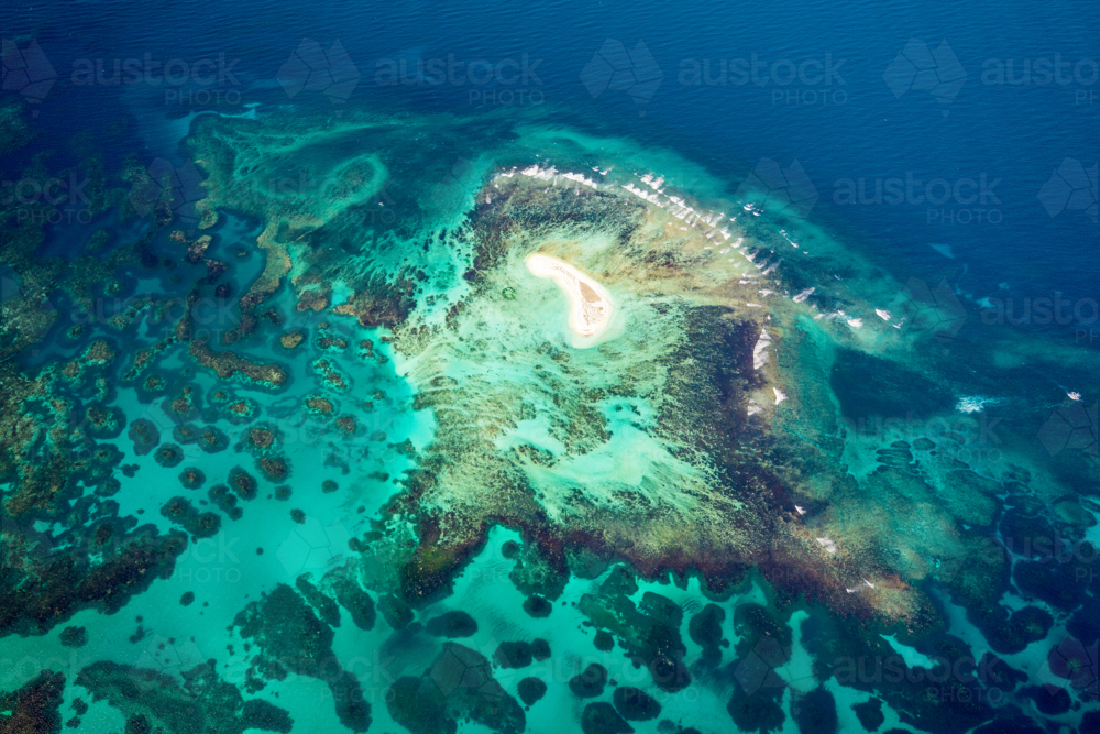 Image of Tiny sandy cay surrounded by vivid coral reef. - Austockphoto