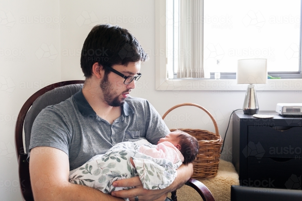 Image of Tired father holding newborn baby daughter in nursery ...
