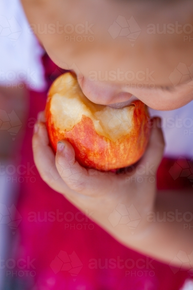 Image of Toddler biting into small apple fruit snack - Austockphoto